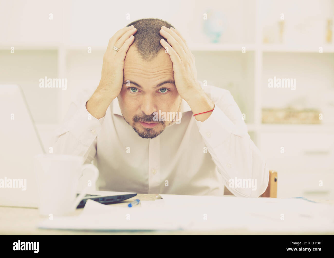 Disappointed worker at his office table feeling stressed, thinking and ...