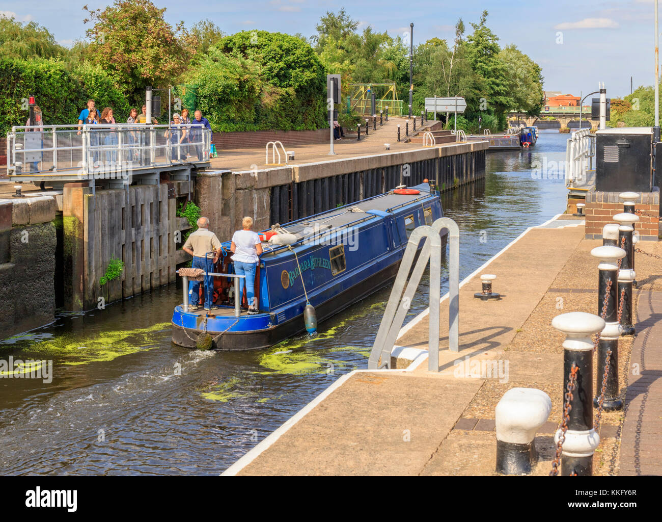 Blue Narrowboat passing through Newark on Trent town lock, with people ...