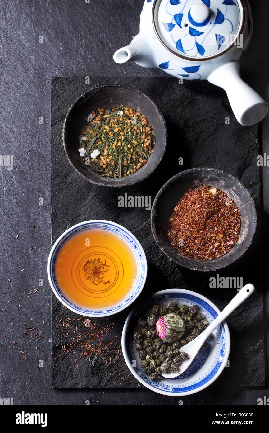 Assortment of dry tea, cup of hot tea and teapot. Green tea, black tae ...