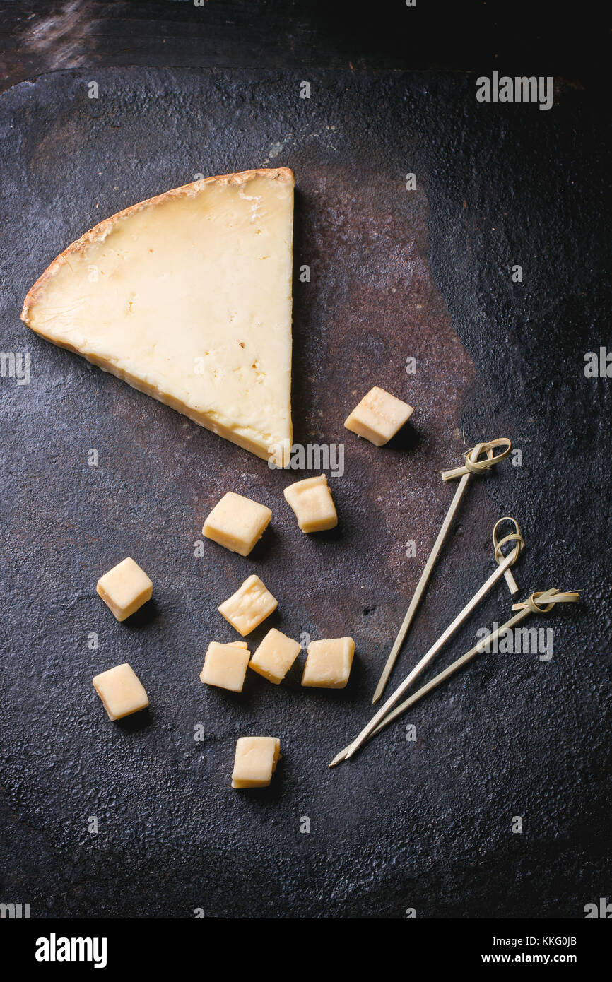Big piece and little cubes of Belgian cheese over black background. Top ...