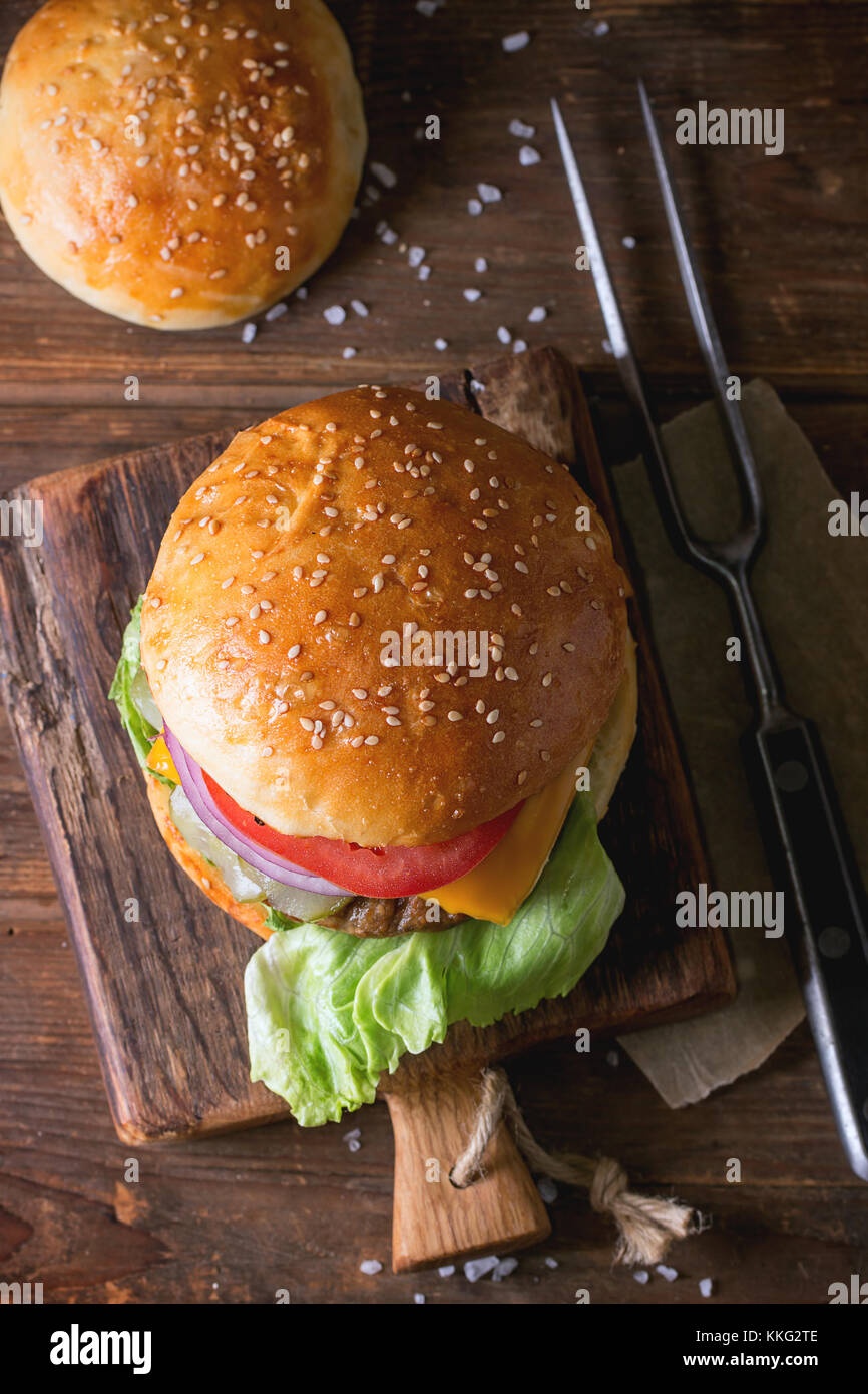 Fresh homemade burger on little cutting board with meat fork over ...
