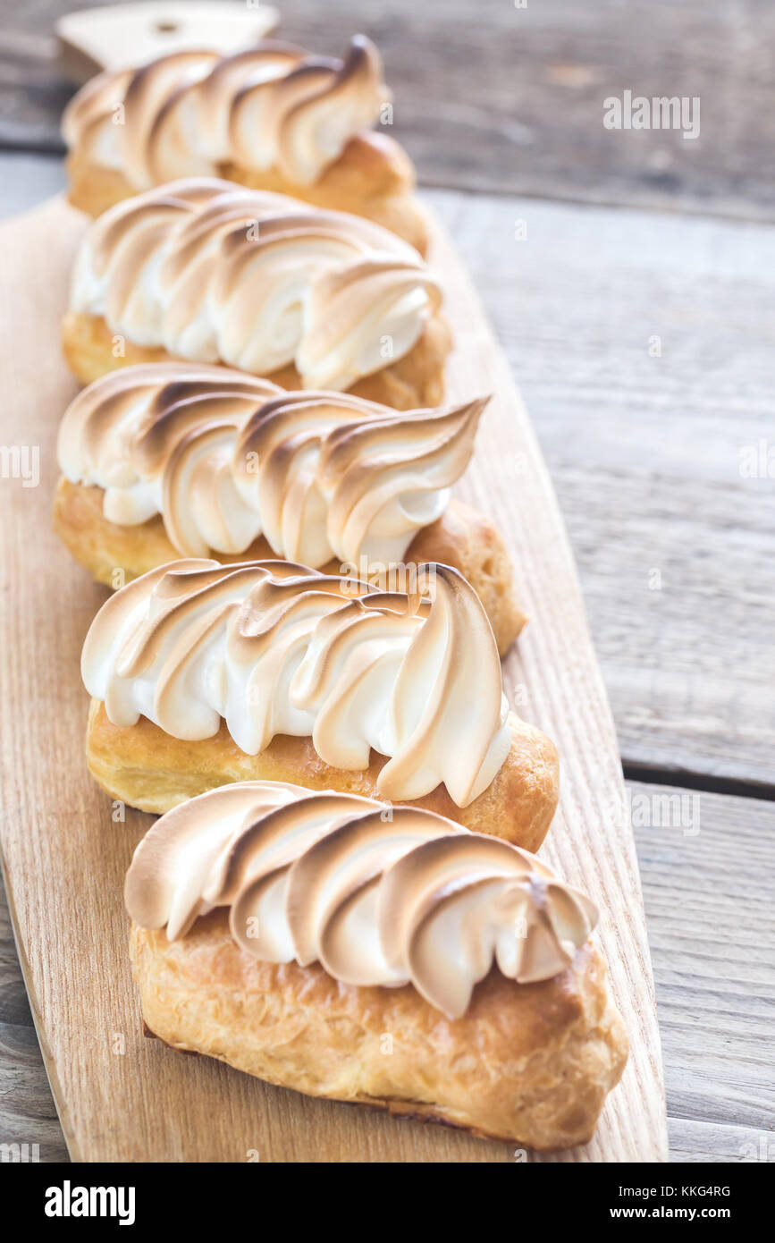 Eclairs with lemon curd and meringue on the wooden board Stock Photo ...