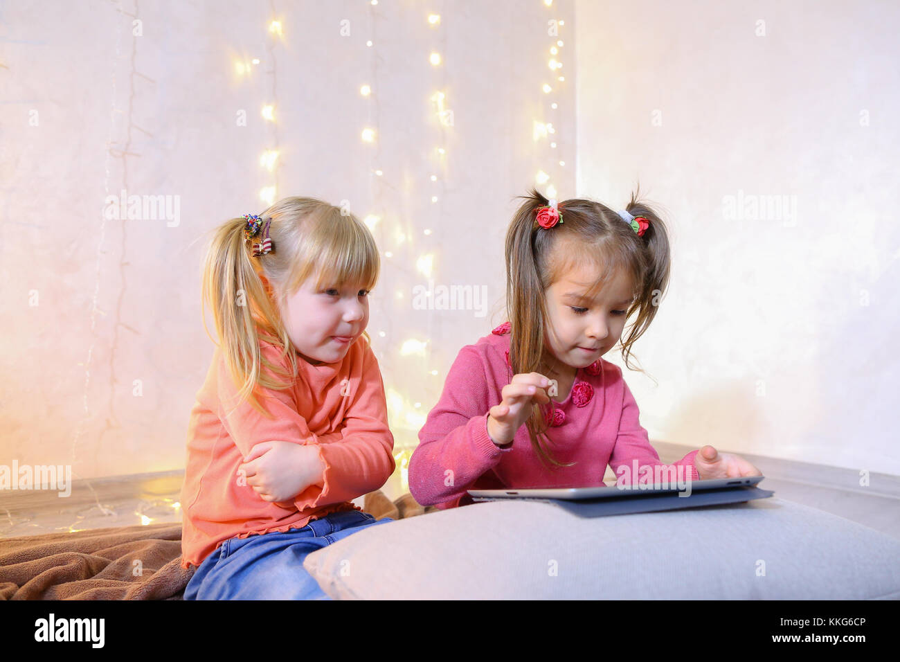 Little girls involved in use of tablet and sit on floor in brigh Stock ...