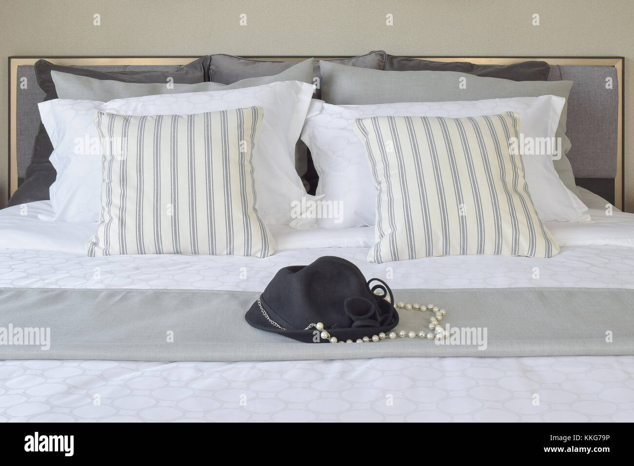 modern bedroom with striped pillows and black hat on bed Stock Photo ...