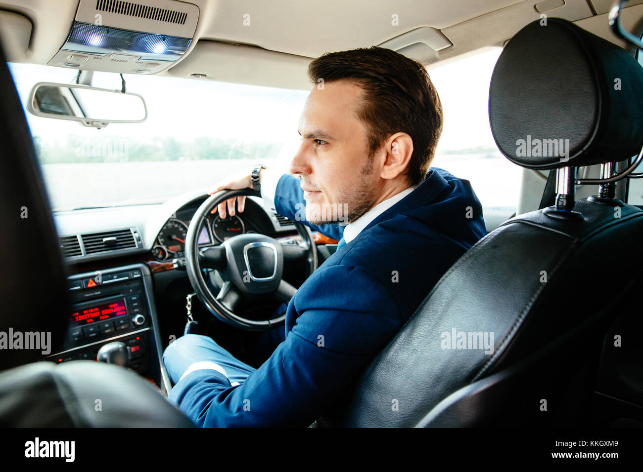 Attractive handsome elegant man in a business suit driving an expensive ...