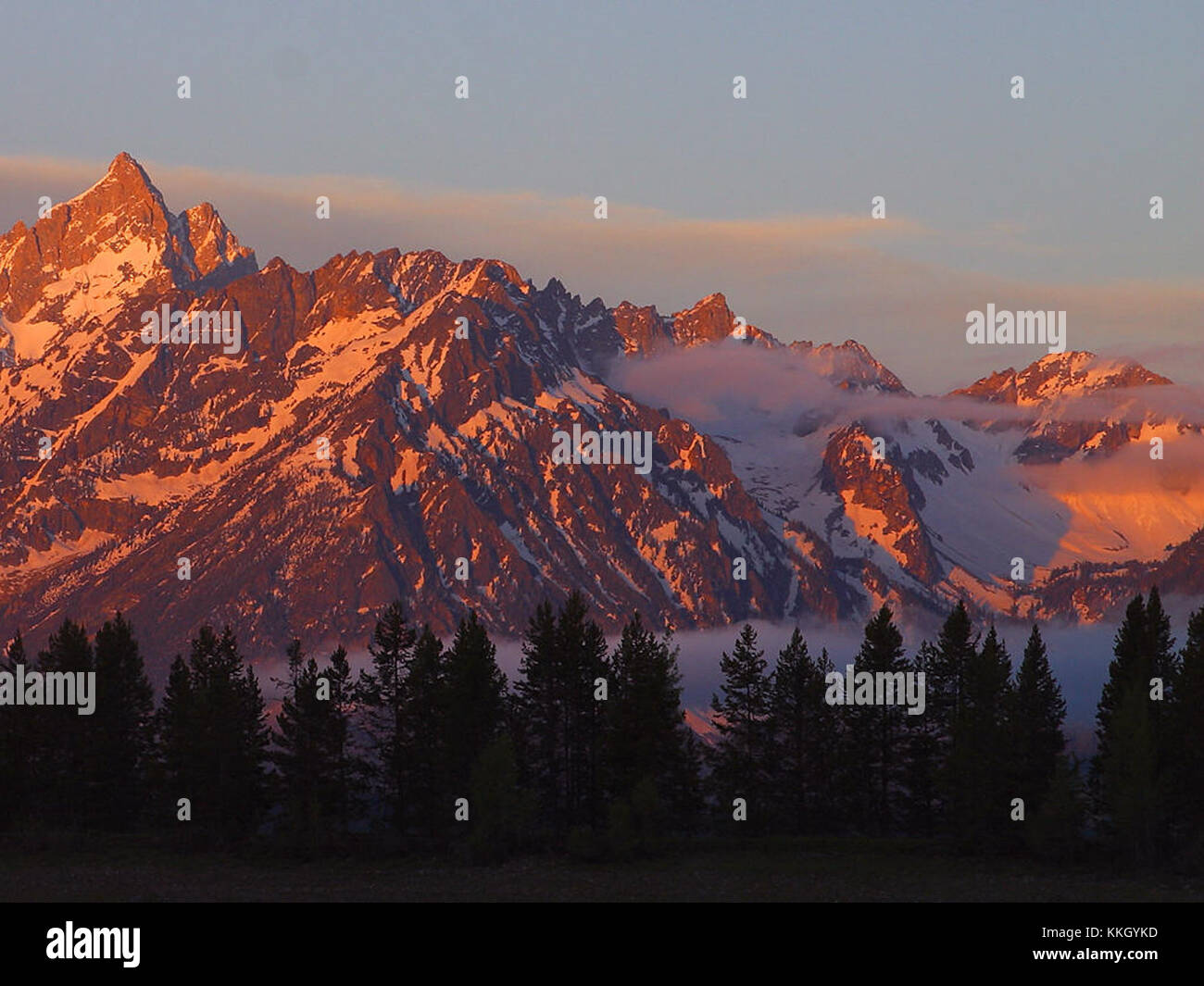 A cropped image of the Grand Tetons during sunrise, capturing the dramatic lighting and ...