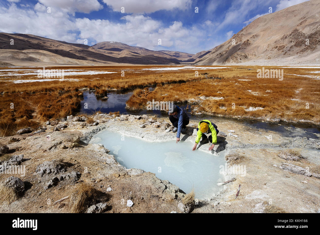 Mother and son touching hot water of a geyser in geothermal area of Puga, Ladakh, Jammu and ...