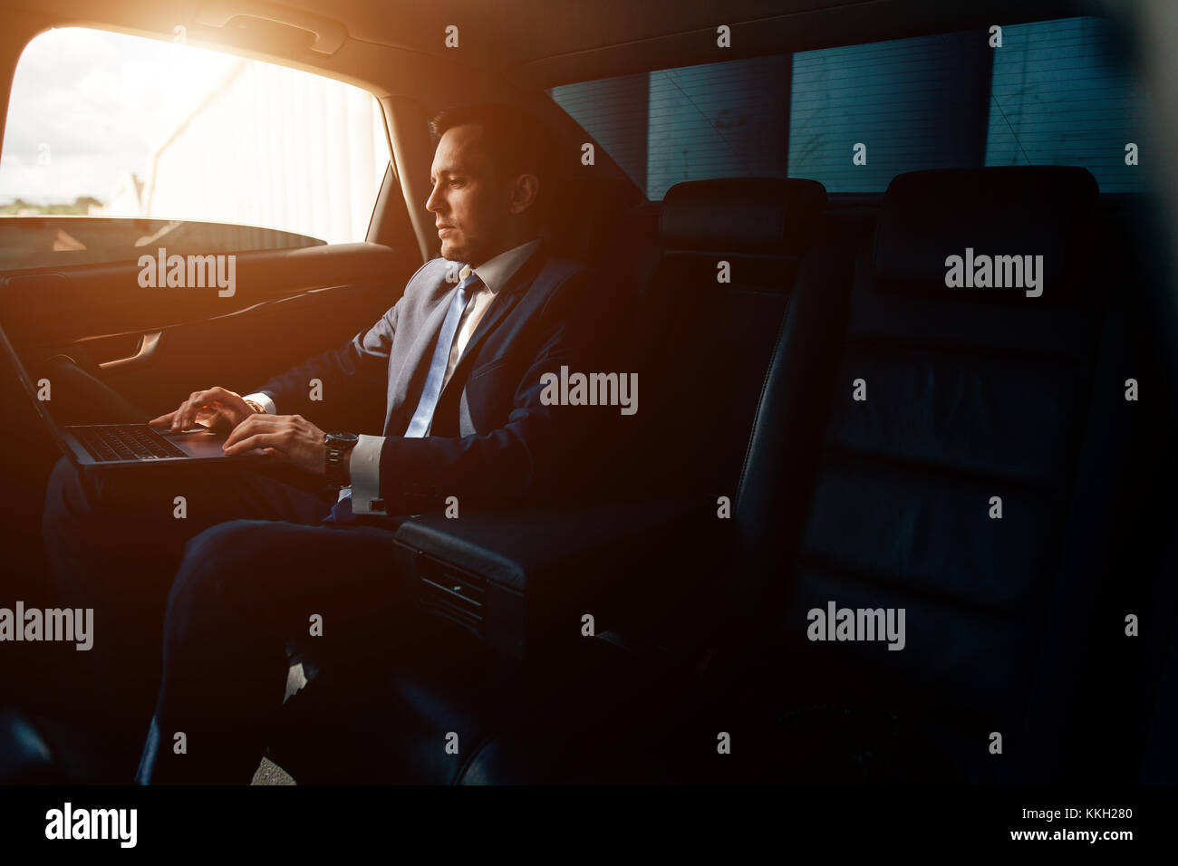 Serious businessman in a car with laptop Stock Photo - Alamy