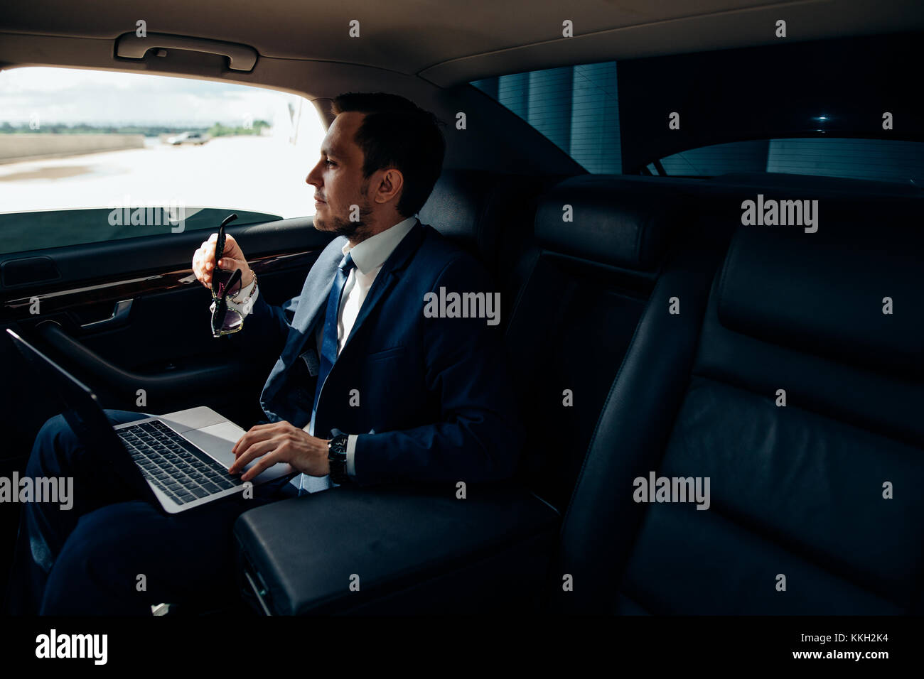 Serious businessman in a car with laptop Stock Photo - Alamy