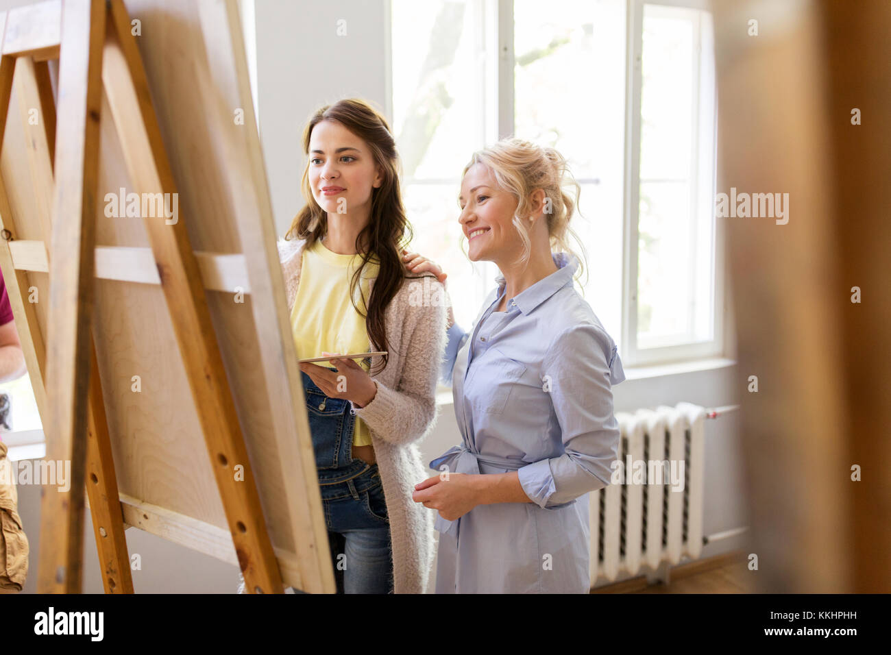 artists discussing painting on easel at art school Stock Photo - Alamy