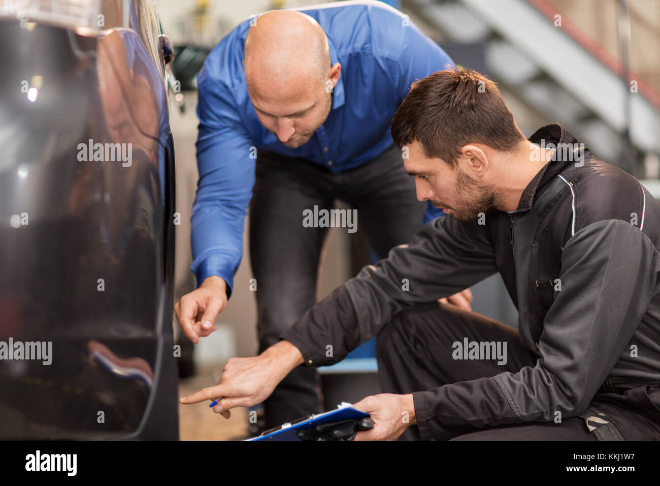 auto mechanic and customer looking at car tire Stock Photo - Alamy