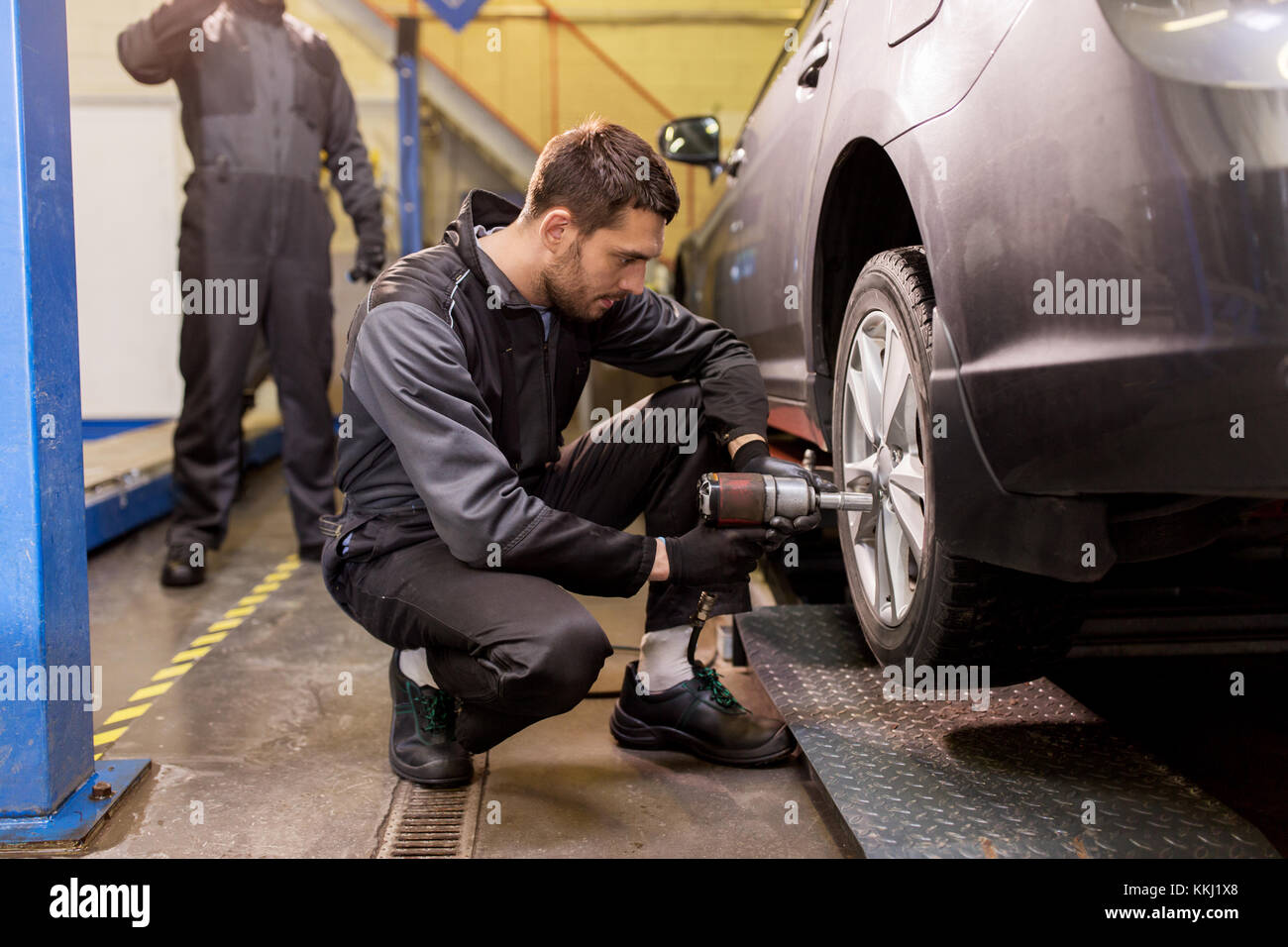 auto mechanic with screwdriver changing car tire Stock Photo - Alamy