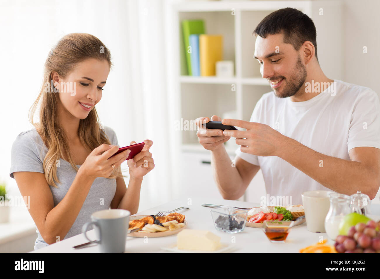couple with smartphones having breakfast at home Stock Photo - Alamy