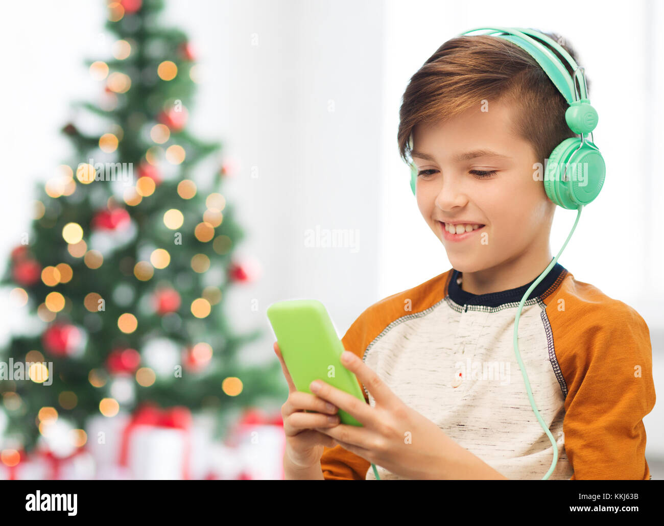 boy with smartphone and headphones at christmas Stock Photo - Alamy