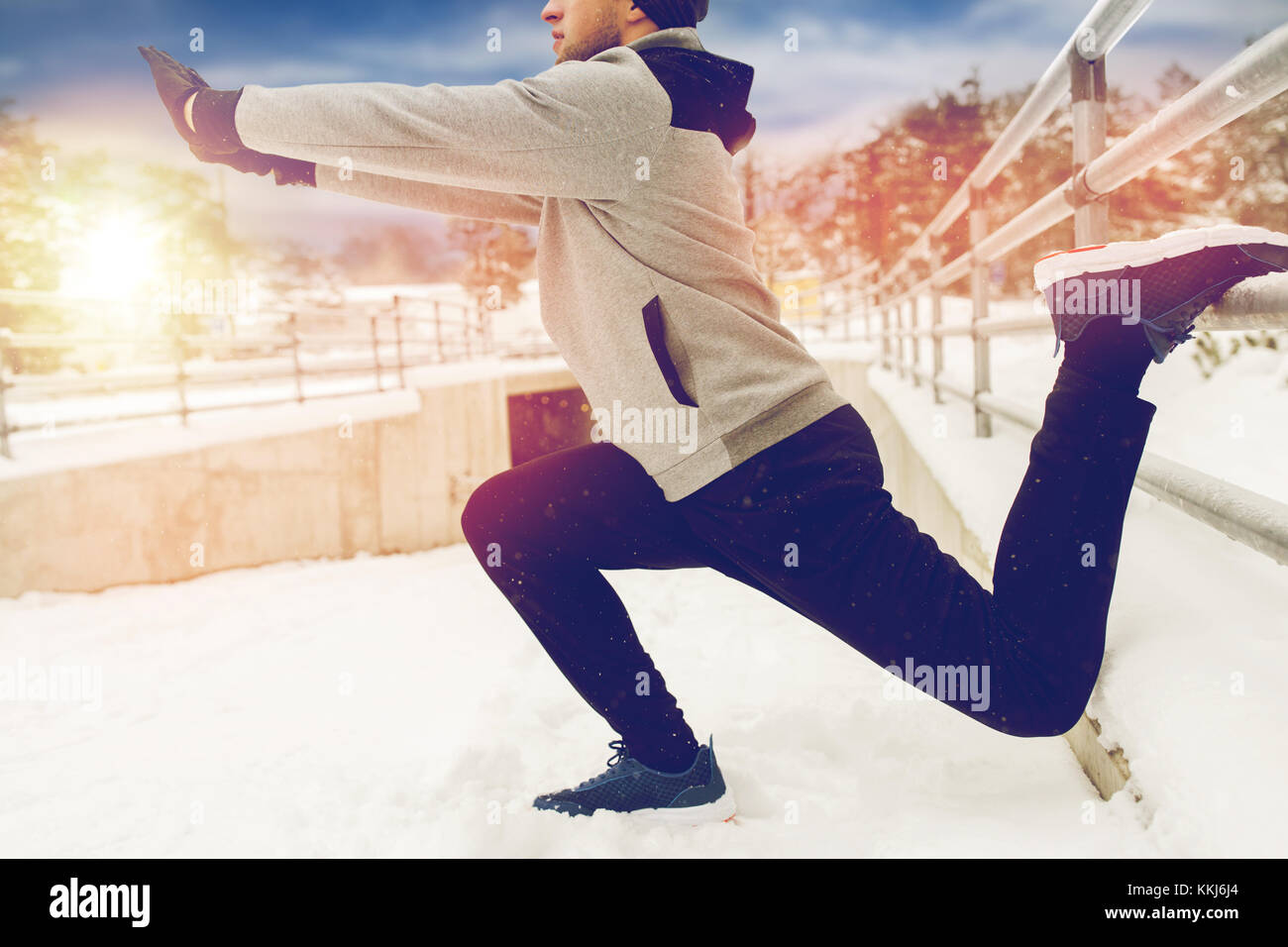 sports man stretching leg at fence in winter Stock Photo - Alamy