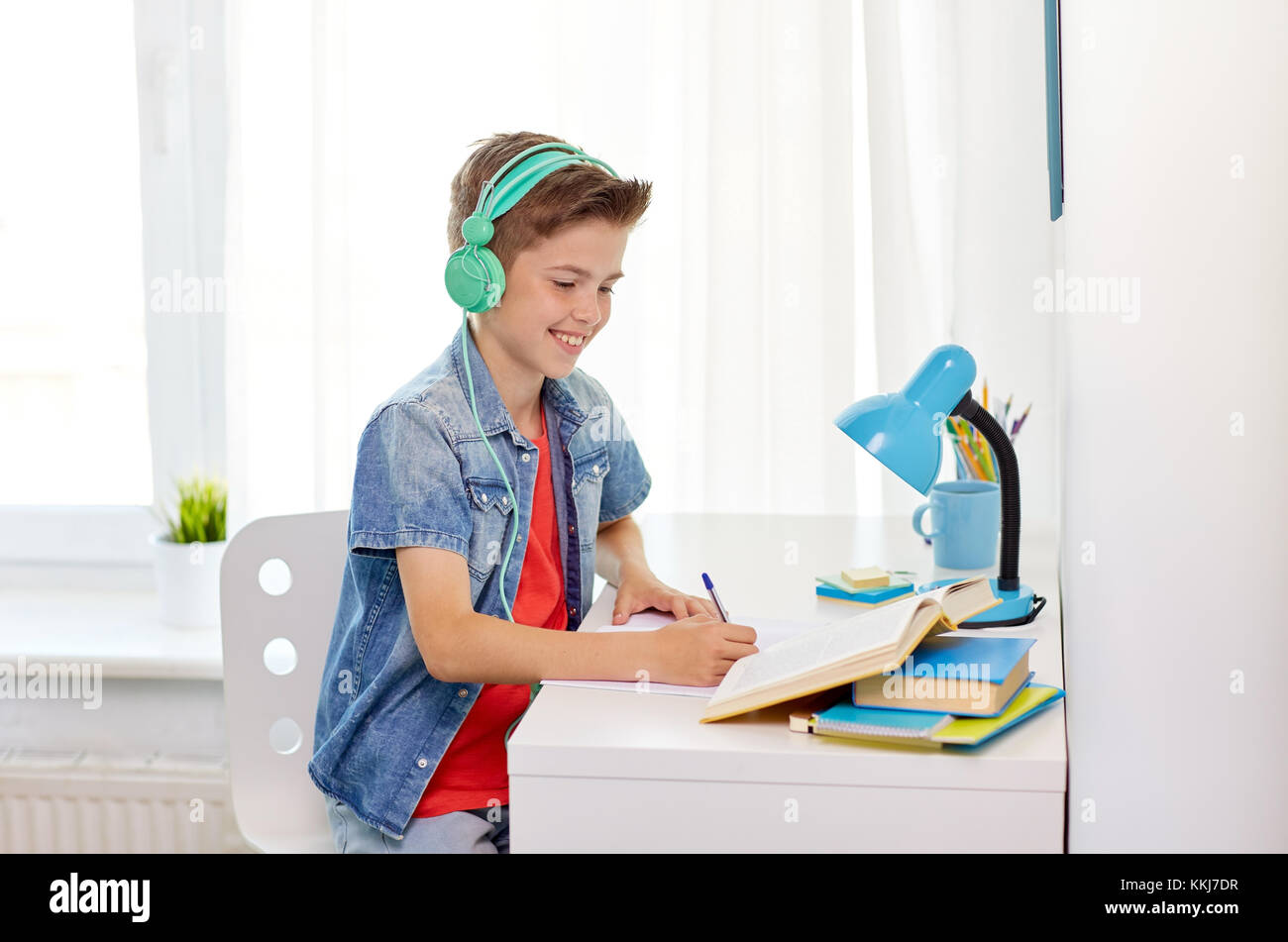 student boy in headphones writing to notebook Stock Photo - Alamy