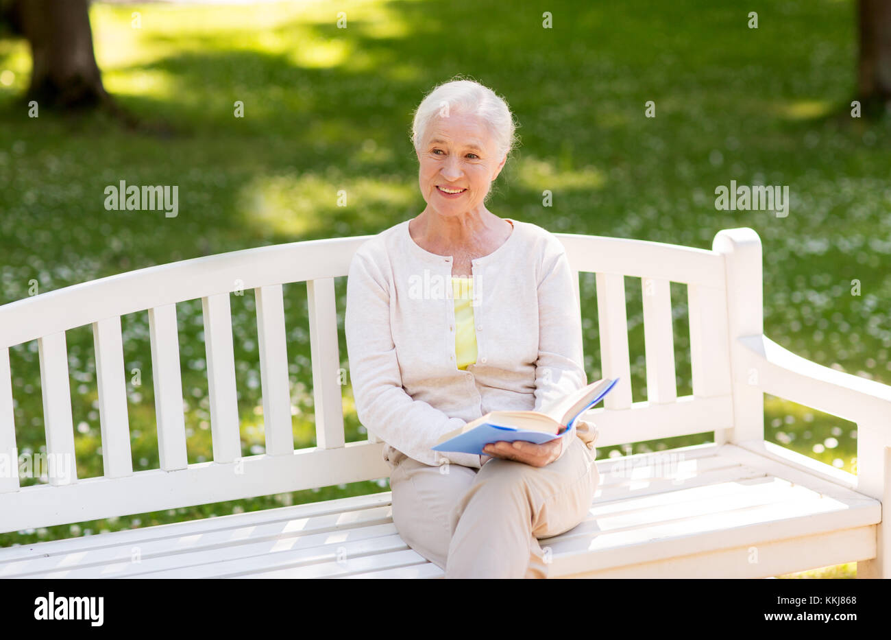 happy senior woman reading book at summer park Stock Photo - Alamy
