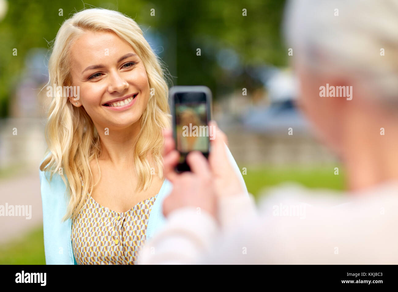 senior mother photographing daughter by smartphone Stock Photo - Alamy
