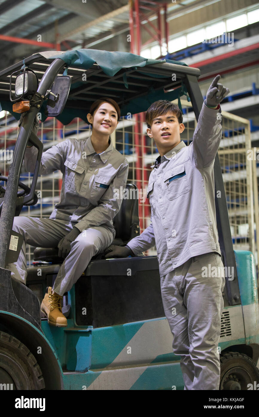 Confident Chinese workers driving forklift in the factory Stock Photo ...