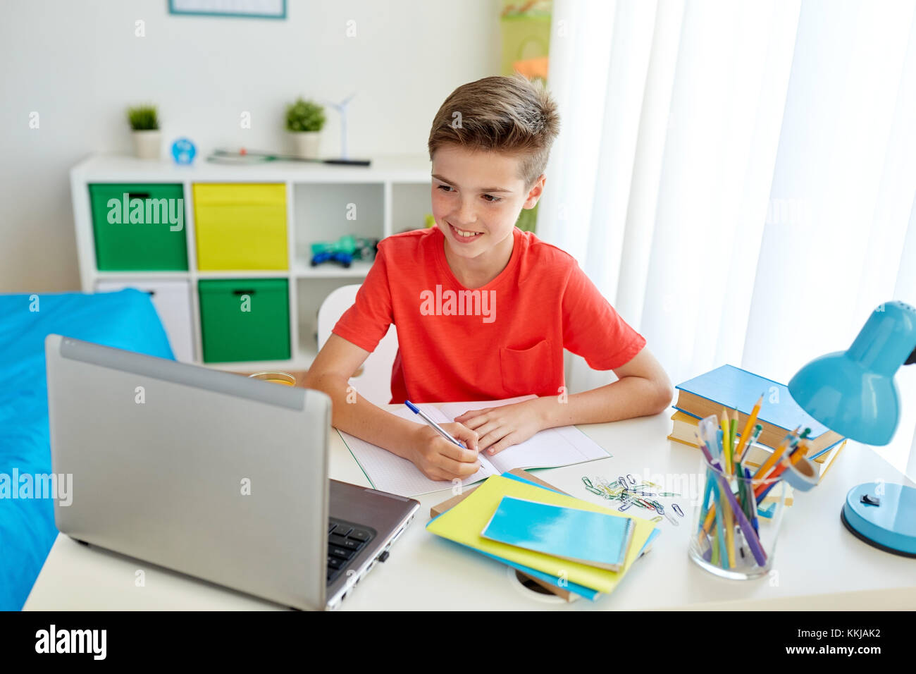 student boy with laptop writing to notebook Stock Photo - Alamy