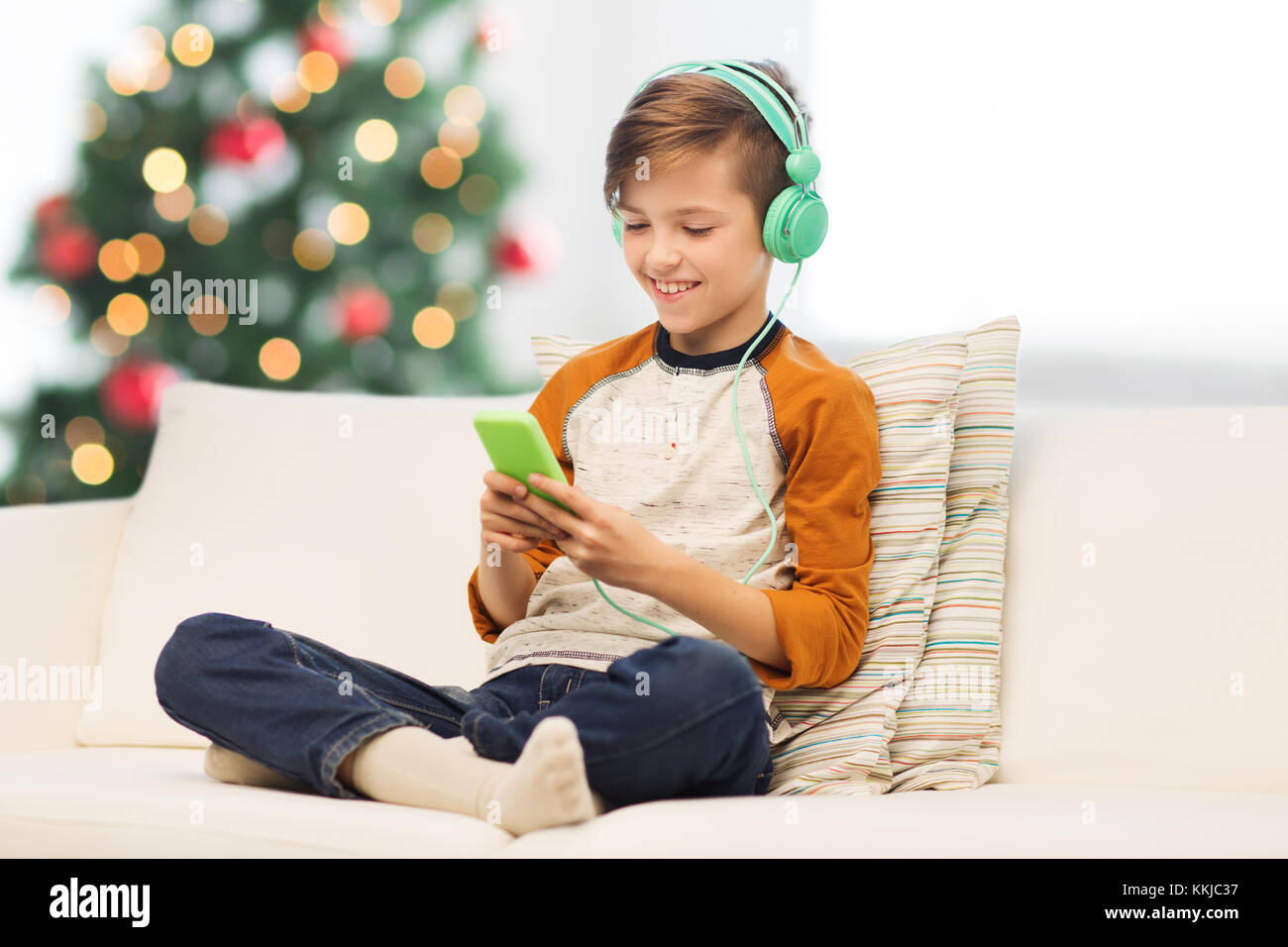 boy with smartphone and headphones at christmas Stock Photo - Alamy