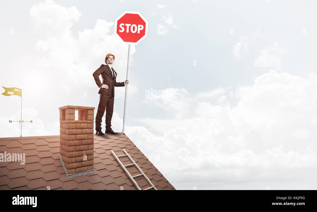 Caucasian businessman on brick house roof showing stop road sign Stock ...