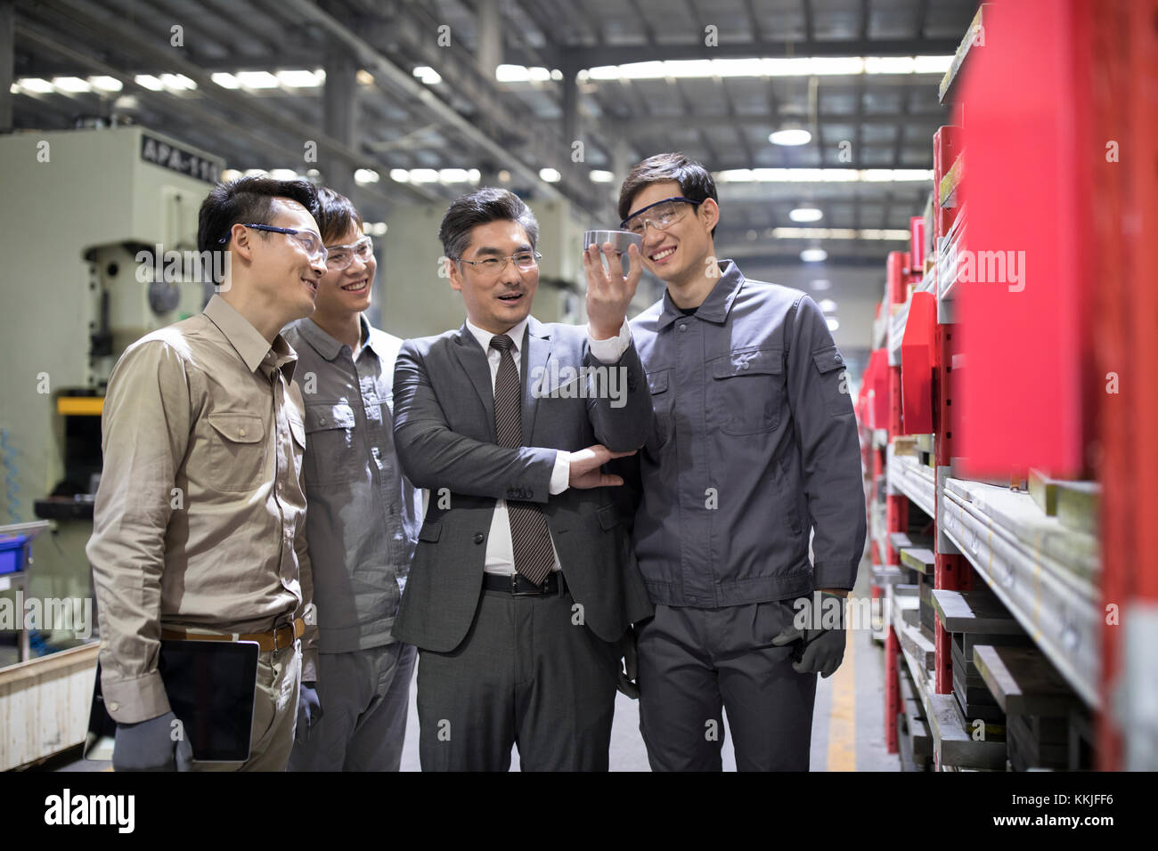 Chinese businessman and engineers checking machine parts in the factory ...