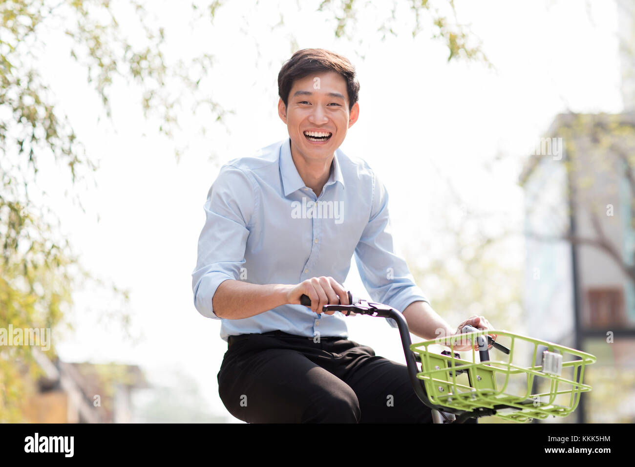 Young Chinese man riding a share bike Stock Photo - Alamy