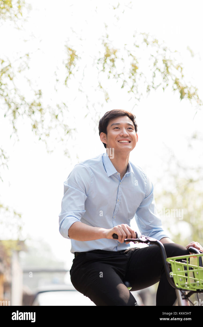 Young Chinese man riding a share bike Stock Photo - Alamy