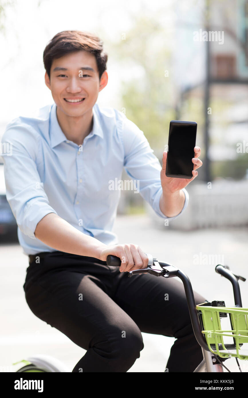 Young Chinese man riding a share bike Stock Photo - Alamy