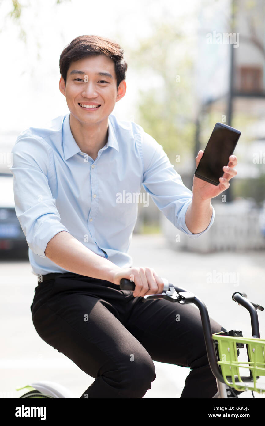 Young Chinese man riding a share bike Stock Photo - Alamy