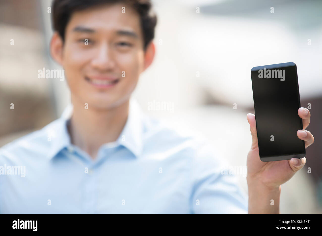 Young Chinese businessman showing a smart phone Stock Photo - Alamy