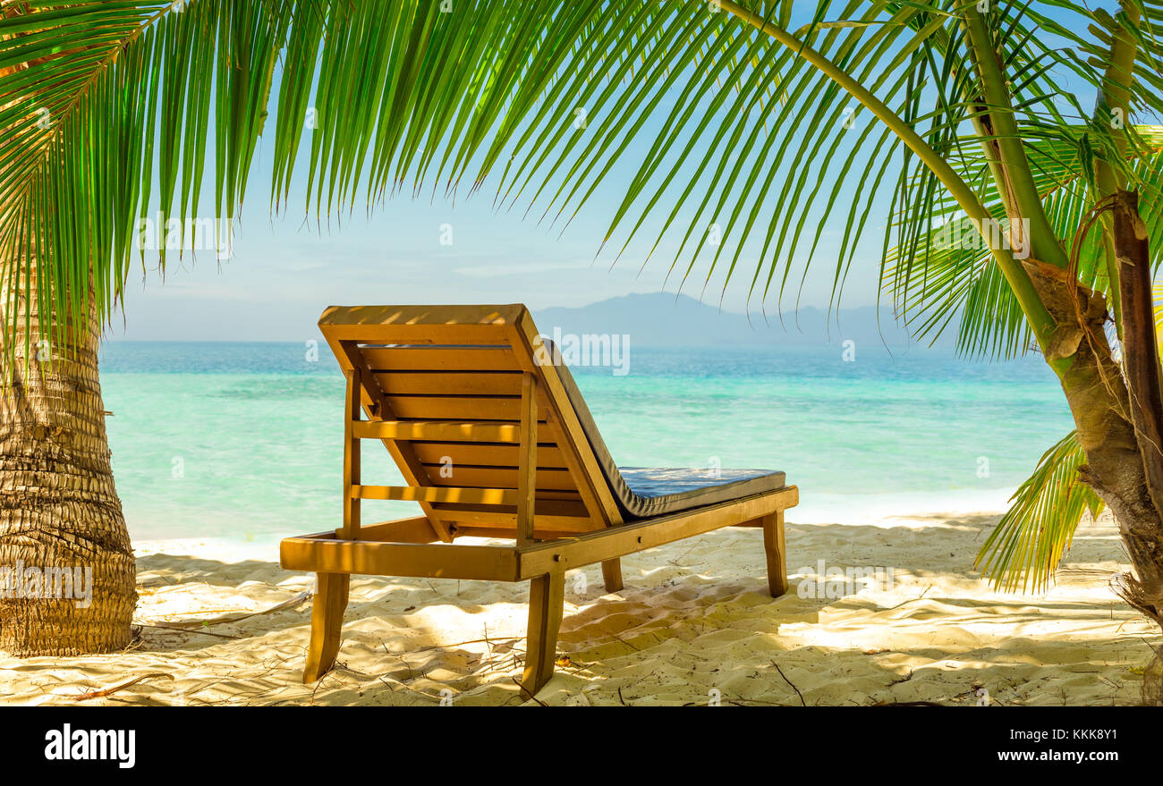 Lounge chair on the beach, in the shade of a palm tree leaf Stock Photo ...