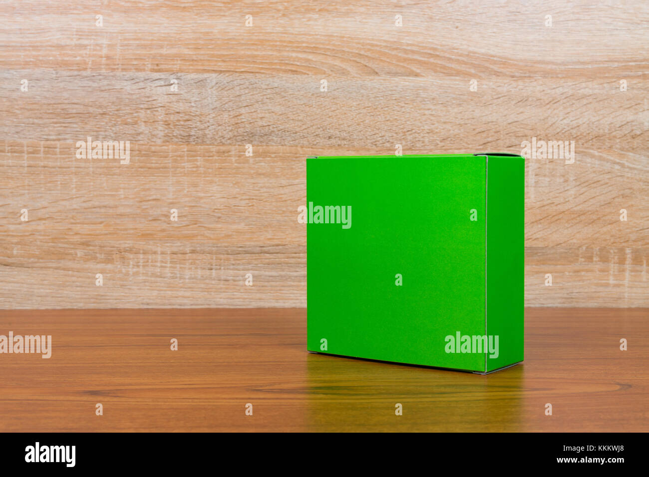 Empty closed green cardboard box for mock up on bright wooden table ...