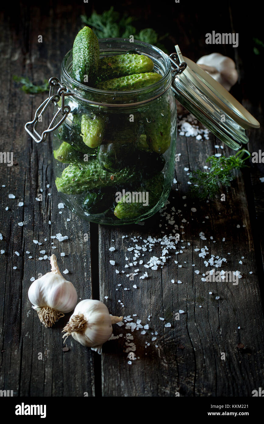Glass jar with fresh low-salt pickled cucumbers. Over black wooden ...