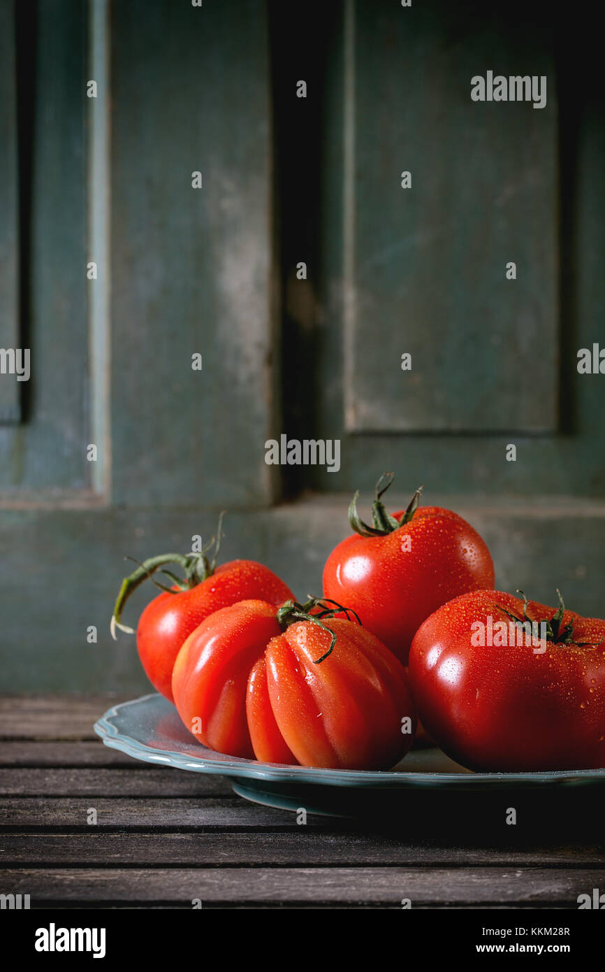 Heap of big red tomatoes RAF on turquoise plate over old wooden table ...