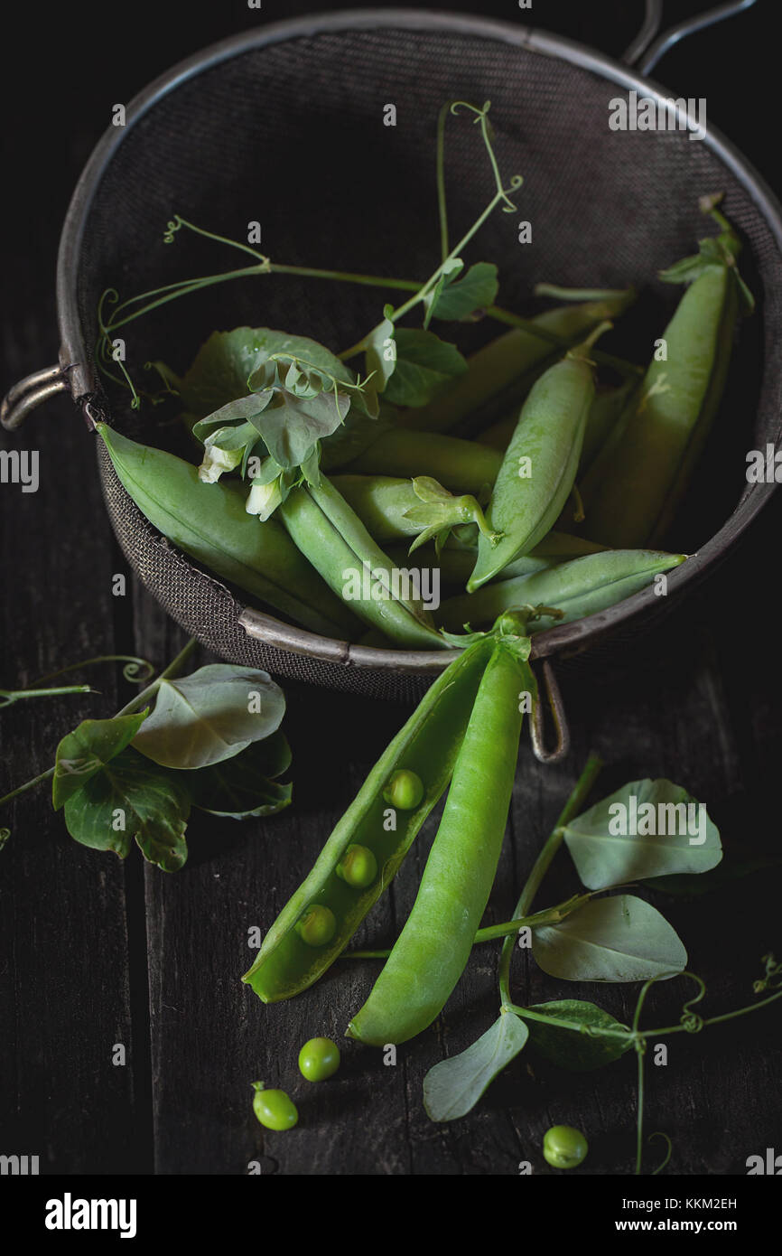 Heap of young green peas whole and broken with leaves and flower in ...