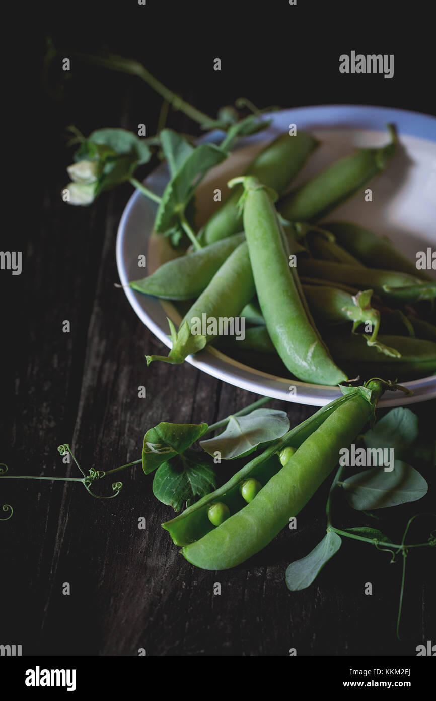 Heap of young green peas whole and broken with leaves and flower in ...