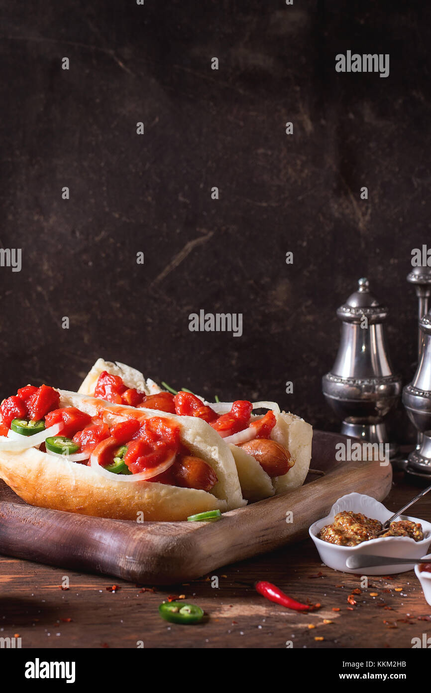 Homemade hot dogs on wooden plate with ingredients mustard, tomato ...