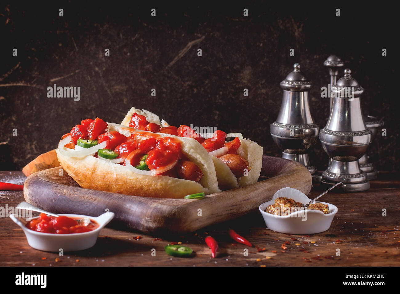 Homemade hot dogs on wooden plate with ingredients mustard, tomato ...
