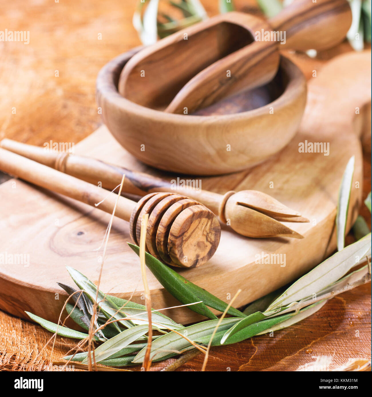 Olive wood kitchen utensil with green olive branch over wooden table ...