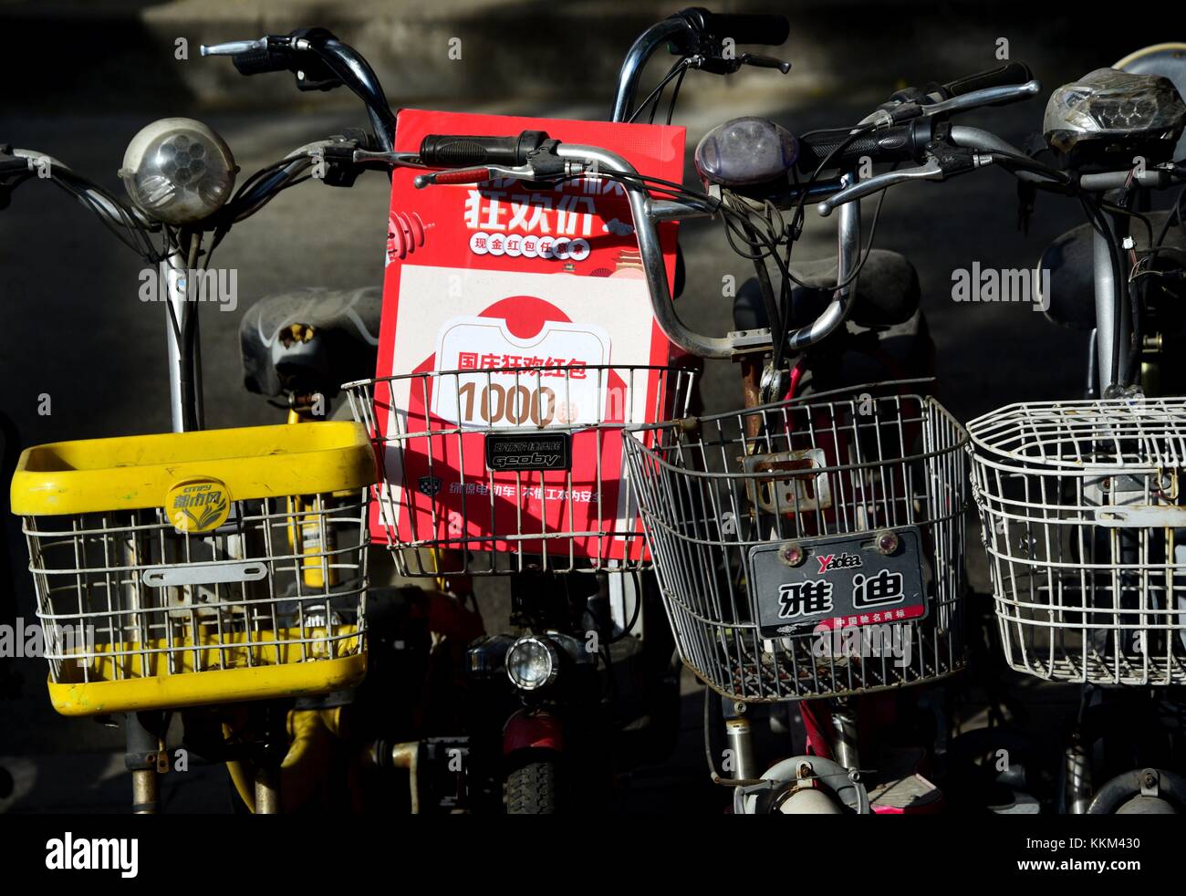 Multiple bikes and e-scooters with baskets near a street in Peking ...