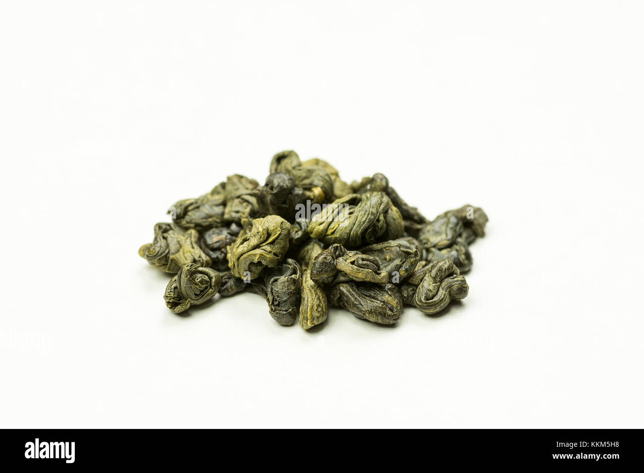 A stack of rolled green tea leaves on a white background Stock Photo ...
