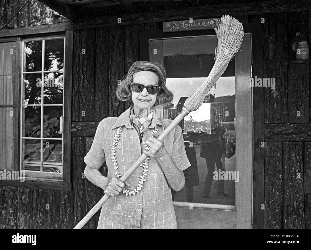An elderly woman wearing a wig and holding a broom Stock Photo - Alamy
