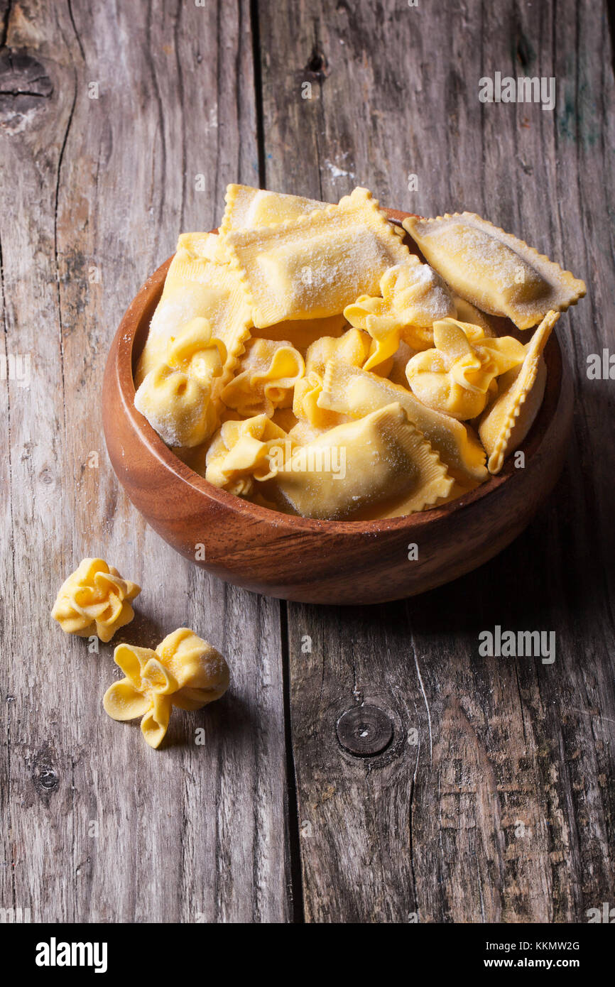 Bowl of raw homemade pasta ravioli and perle over old wooden table ...