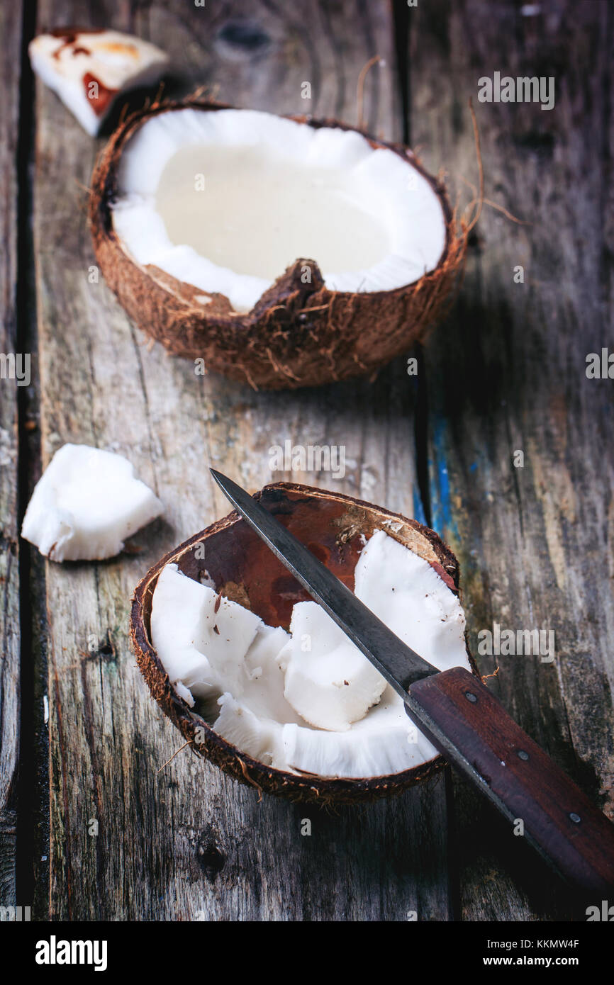 Broken coconut with vintage knife on old wooden table. See series Stock ...