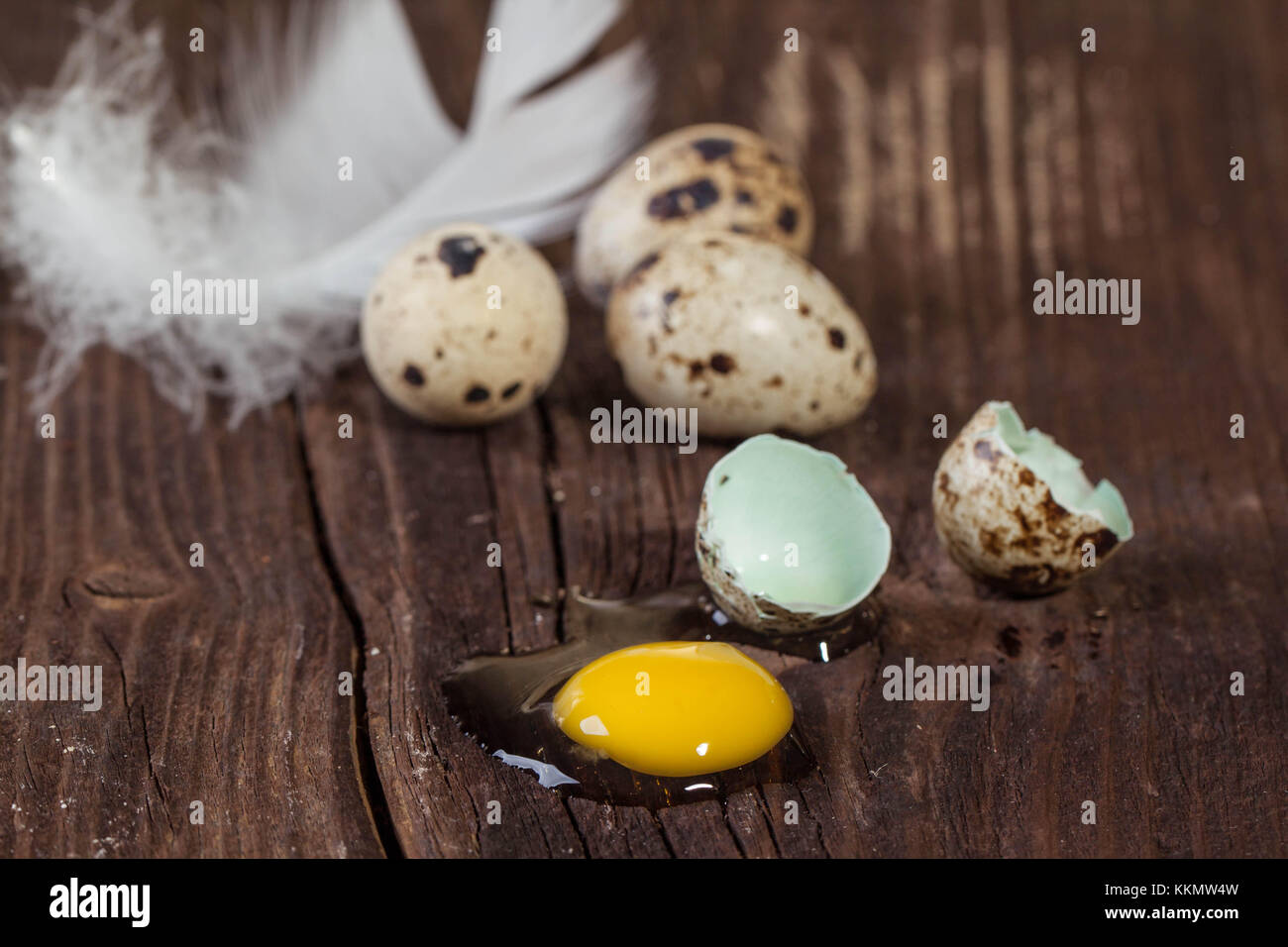 broken quail egg with the leaked yolk on old wooden table Stock Photo ...