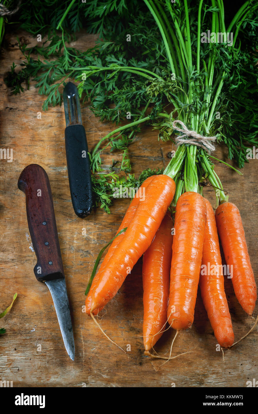 Bunch of fresh carrot with vintage knife on old cutting board. Top view ...