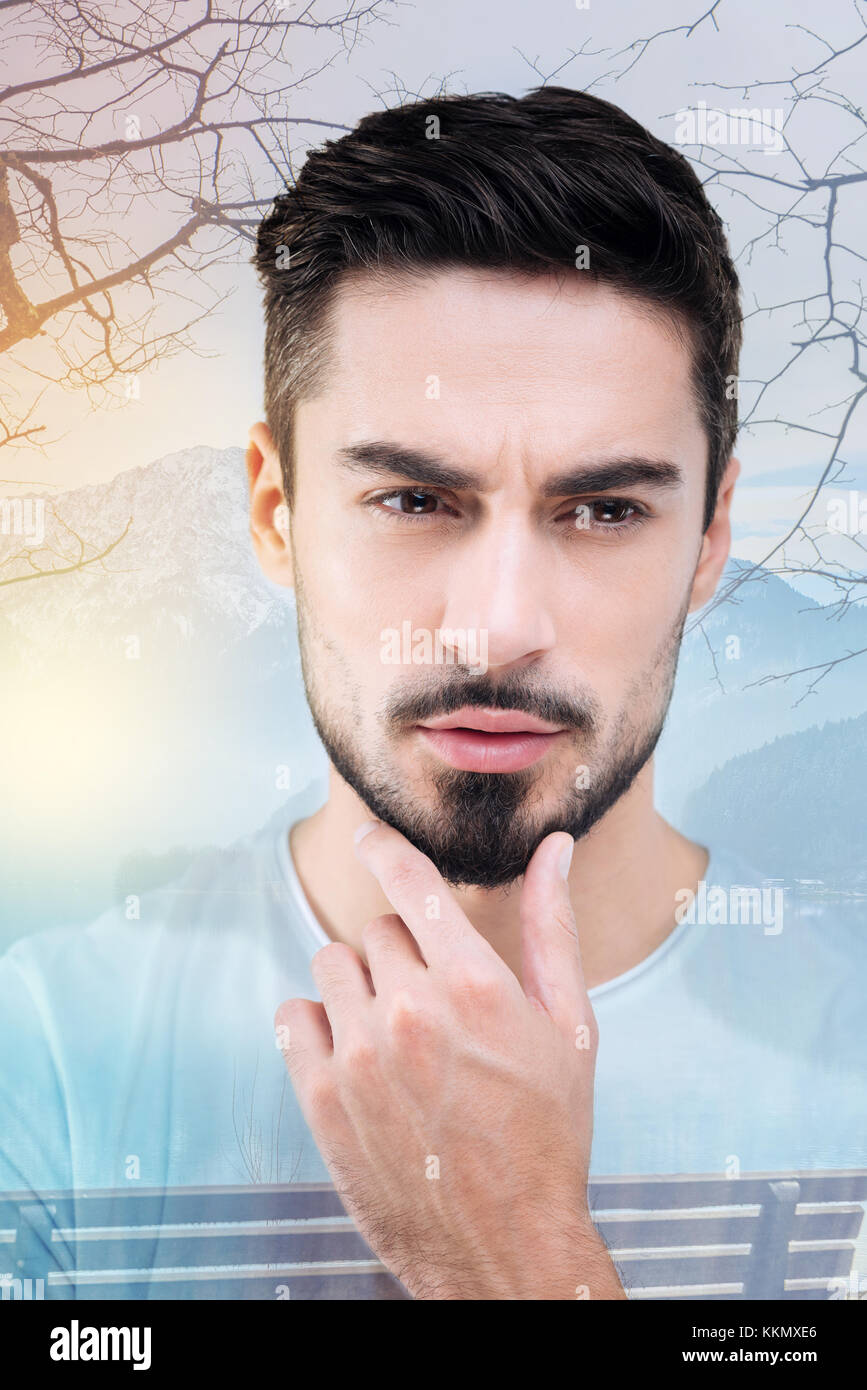 Serious young man touching beard Stock Photo - Alamy