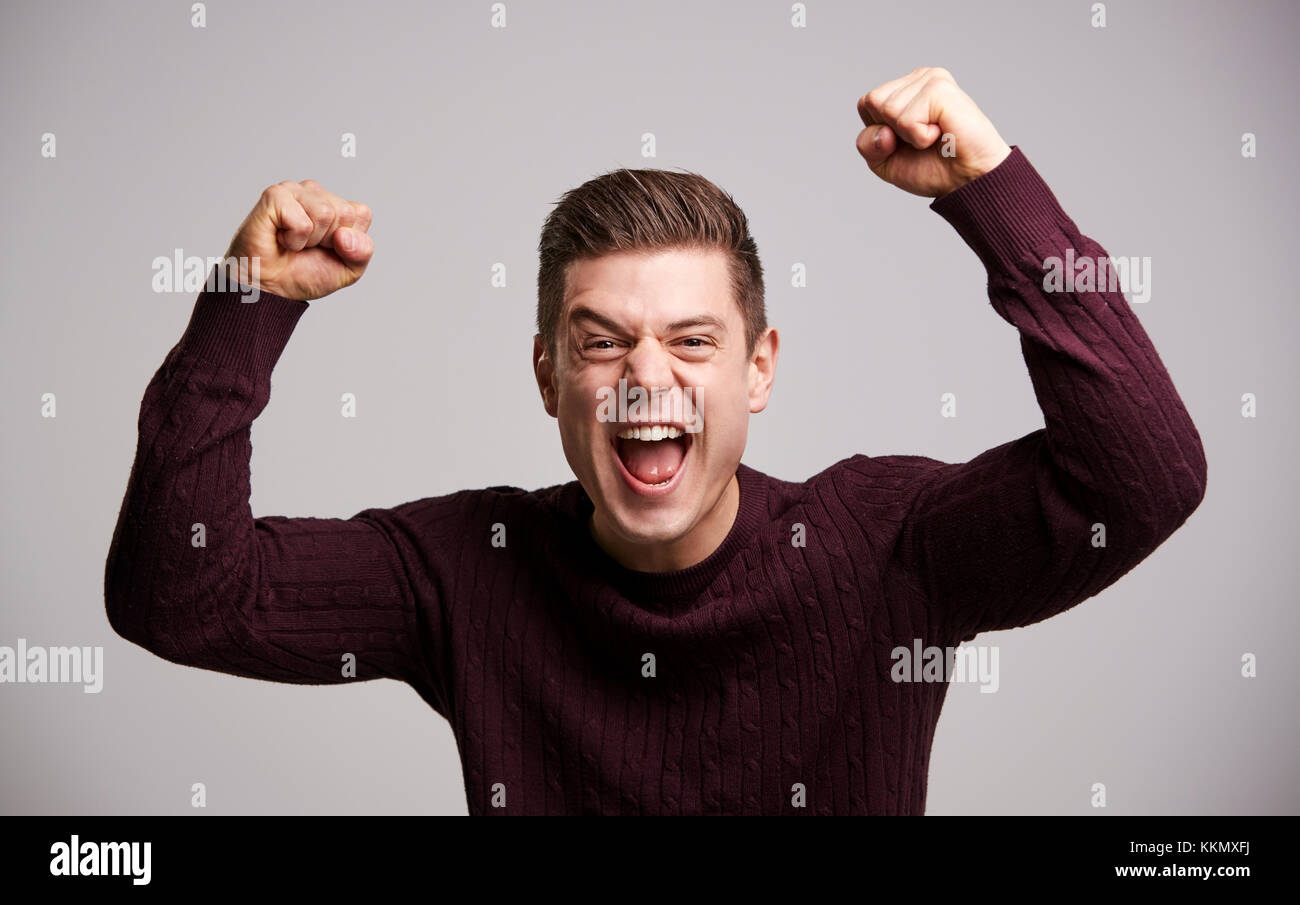 Portrait of a celebrating young white man with arms up Stock Photo - Alamy